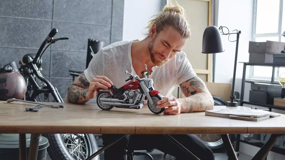 Masada oturan bir adam LEGO motosikletinə baxır.