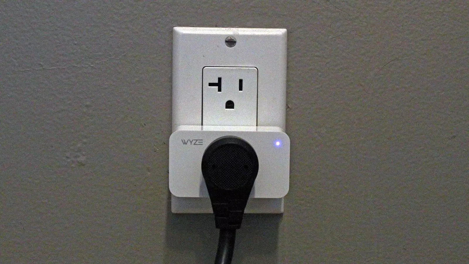 Een Wyze Plug in een stopcontact, met een apparaat erop.