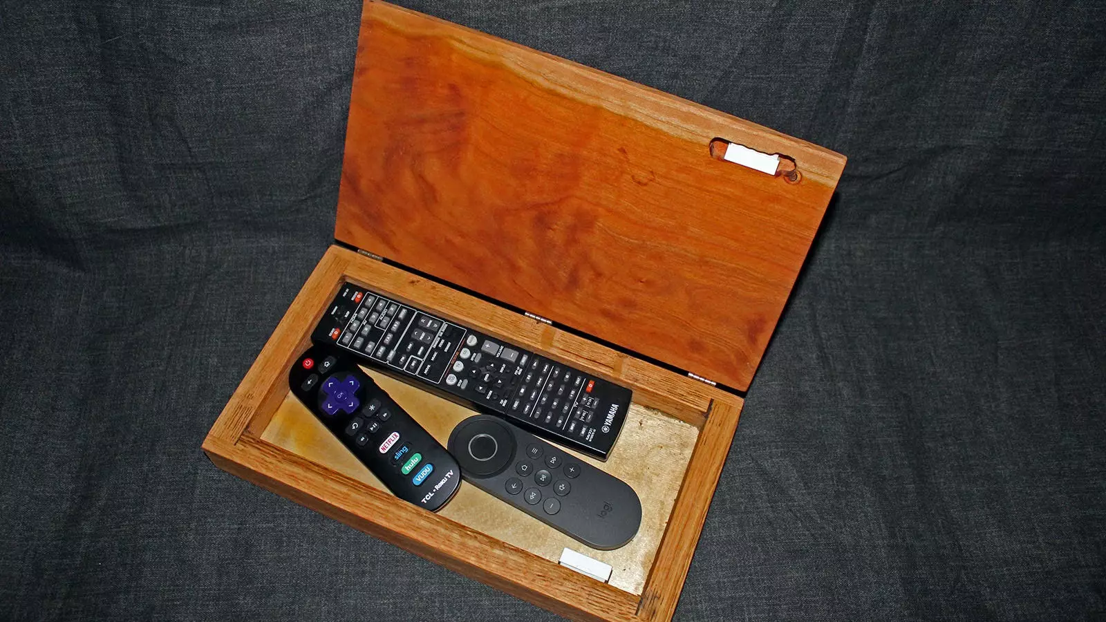 Vnútro krabice s tromi TV diaľkovými ovládačmi a kontaktným senzorom Wyze.