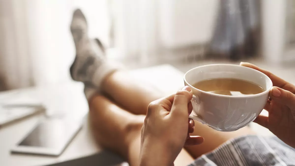 Une personne se détend et boit son café du matin.