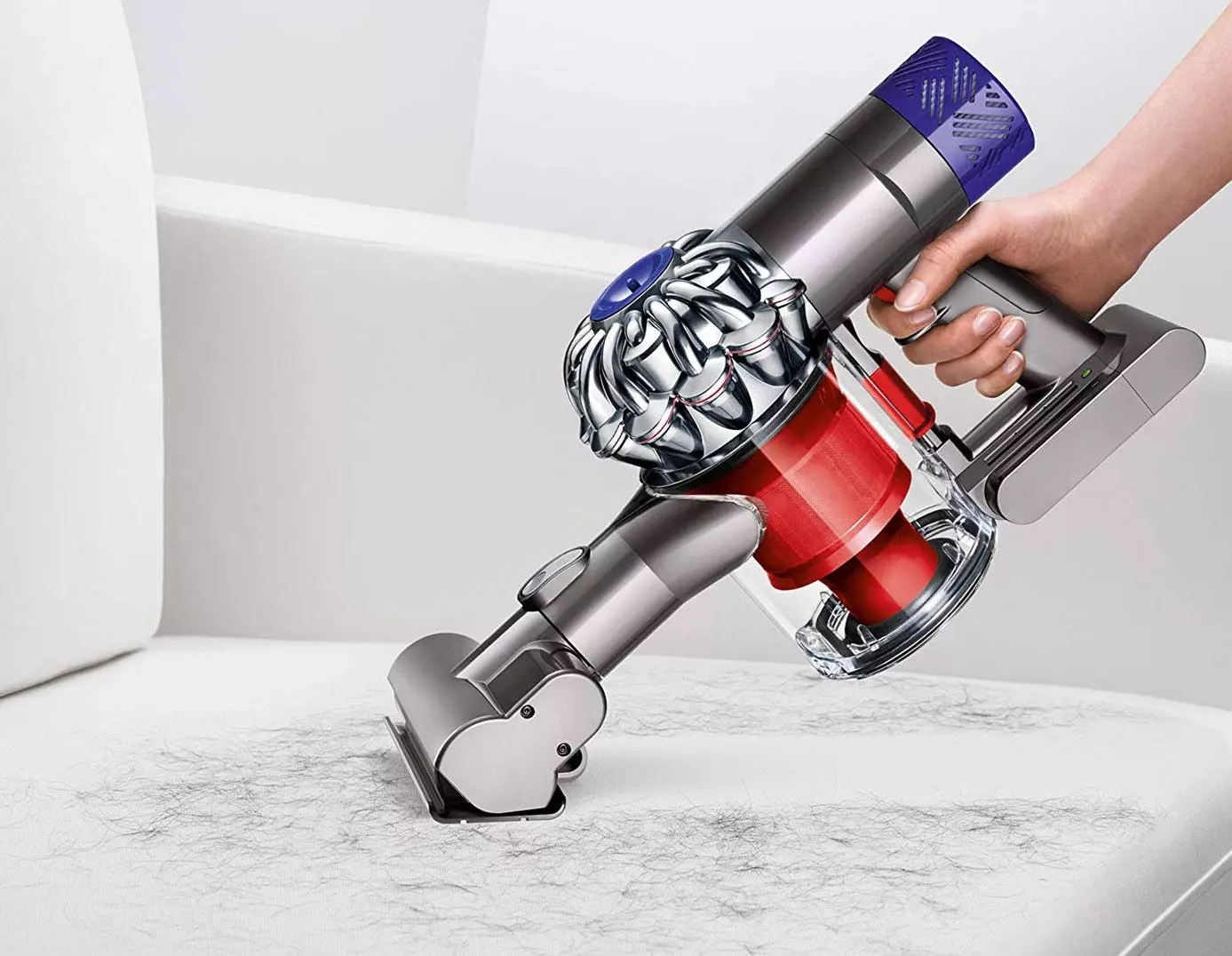 Usa ka handheld Dyson vacuum nga naglimpyo sa buhok ug balhibo sa usa ka lingkuranan.