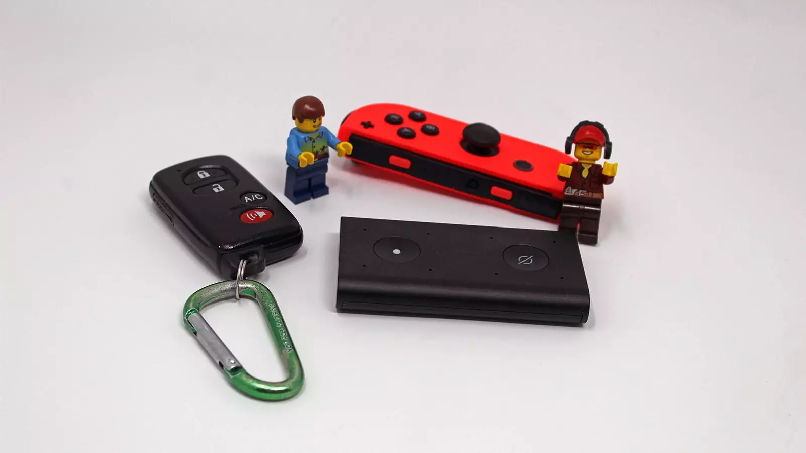 Sebuah Echo di sebelah key fob Prius, Nintendo Joy-Con dan dua minifigs lego.