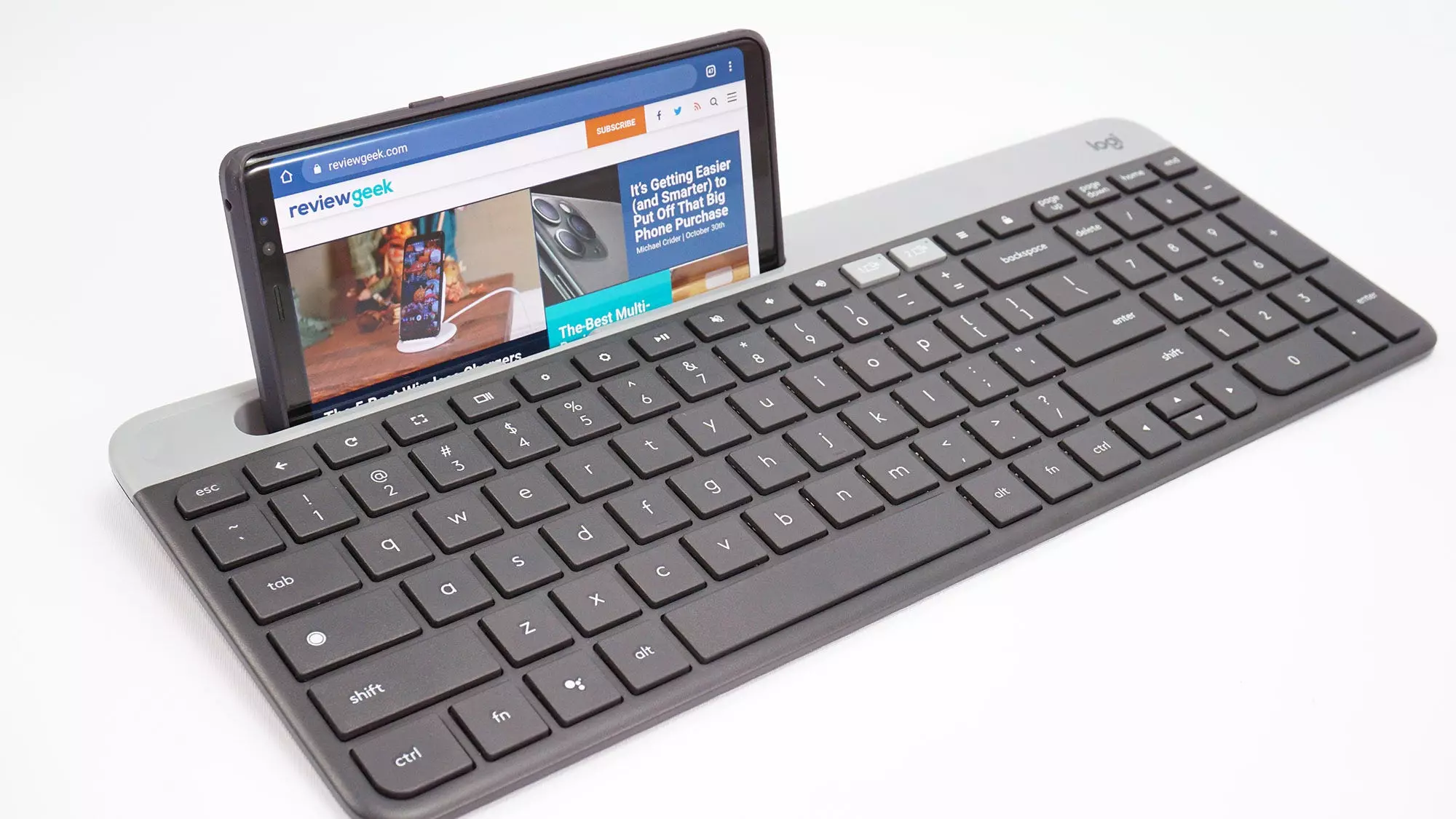 Logitech K580 कीबोर्ड डिव्हाइस ट्रेमध्ये स्मार्टफोन धरून आहे.