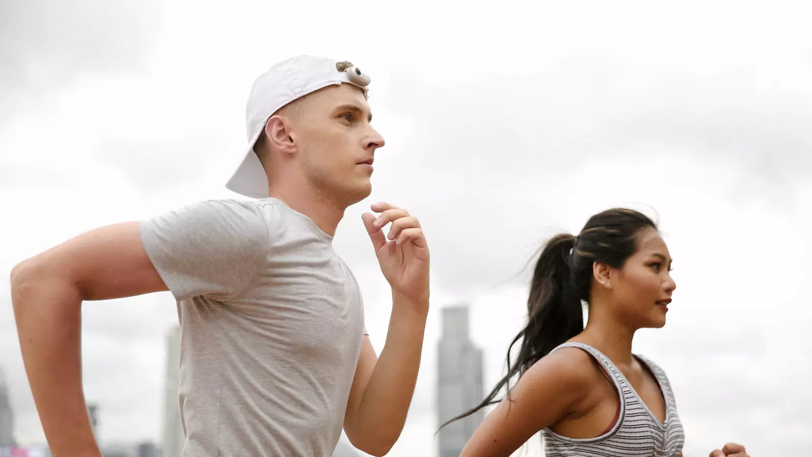 Двама души тичат, като един човек носи Insta360 Go, монтиран на шапката им.