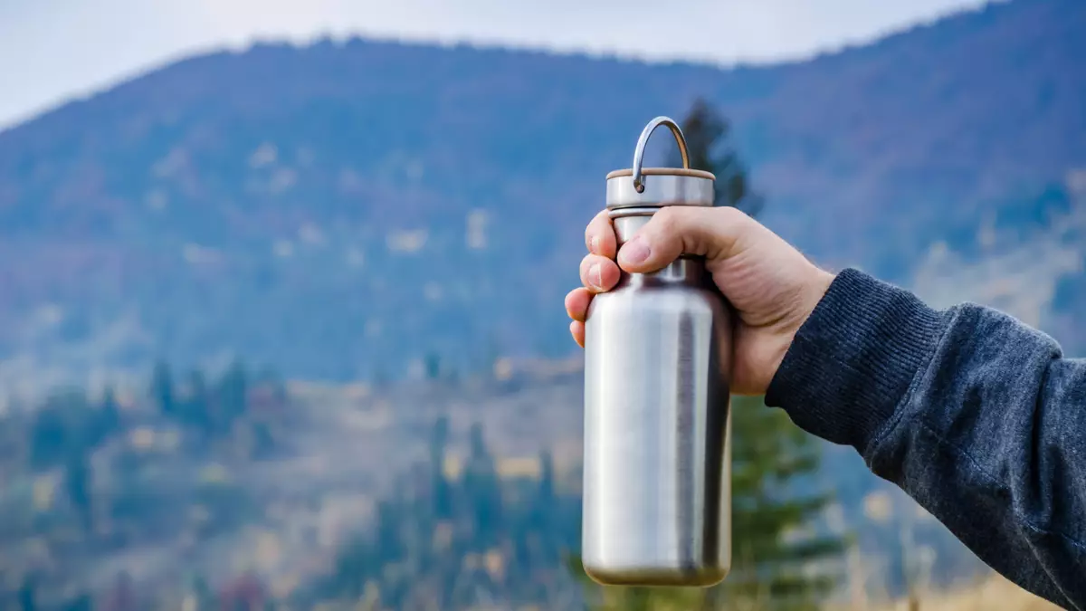 Holder en vandflaske foran et bjerg
