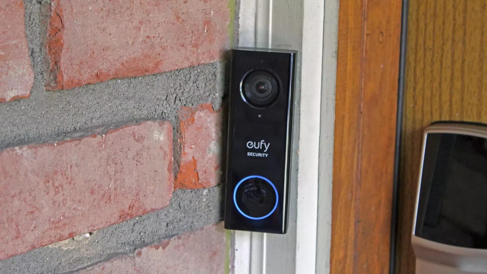 Bel Video Eufy dipasang di pintu dengan tombol menyala biru.