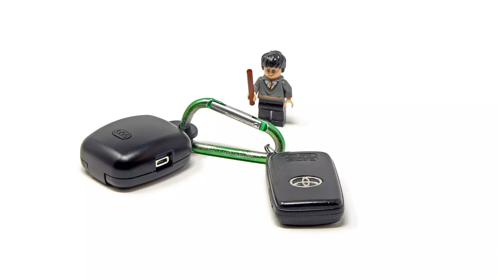 Der GeoZilla-GPS-Tracker, der an einem ähnlich großen Schlüsselanhänger in der Nähe einer Harry-Potter-Lego-Minifigur befestigt ist.