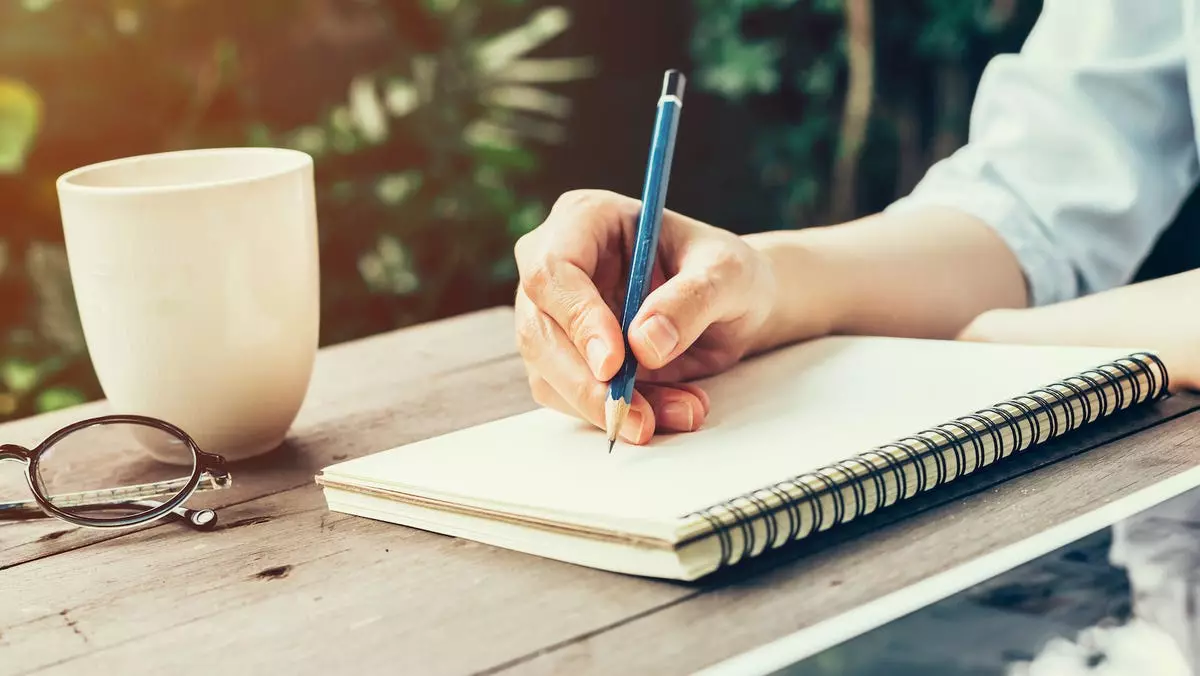 دست زن با مداد نوشتن روی دفترچه در کافی شاپ