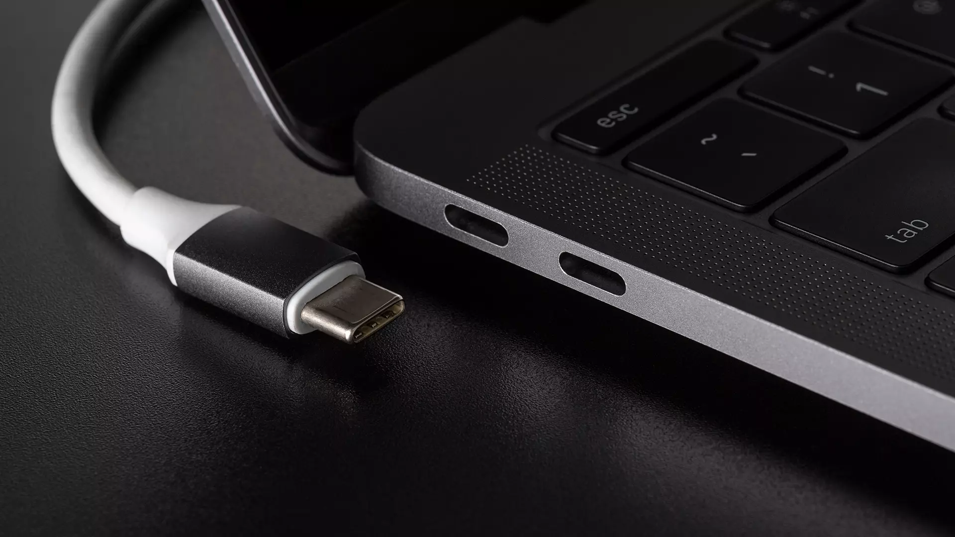 USB-C kabelis, kas atrodas blakus portam MacBook datorā.