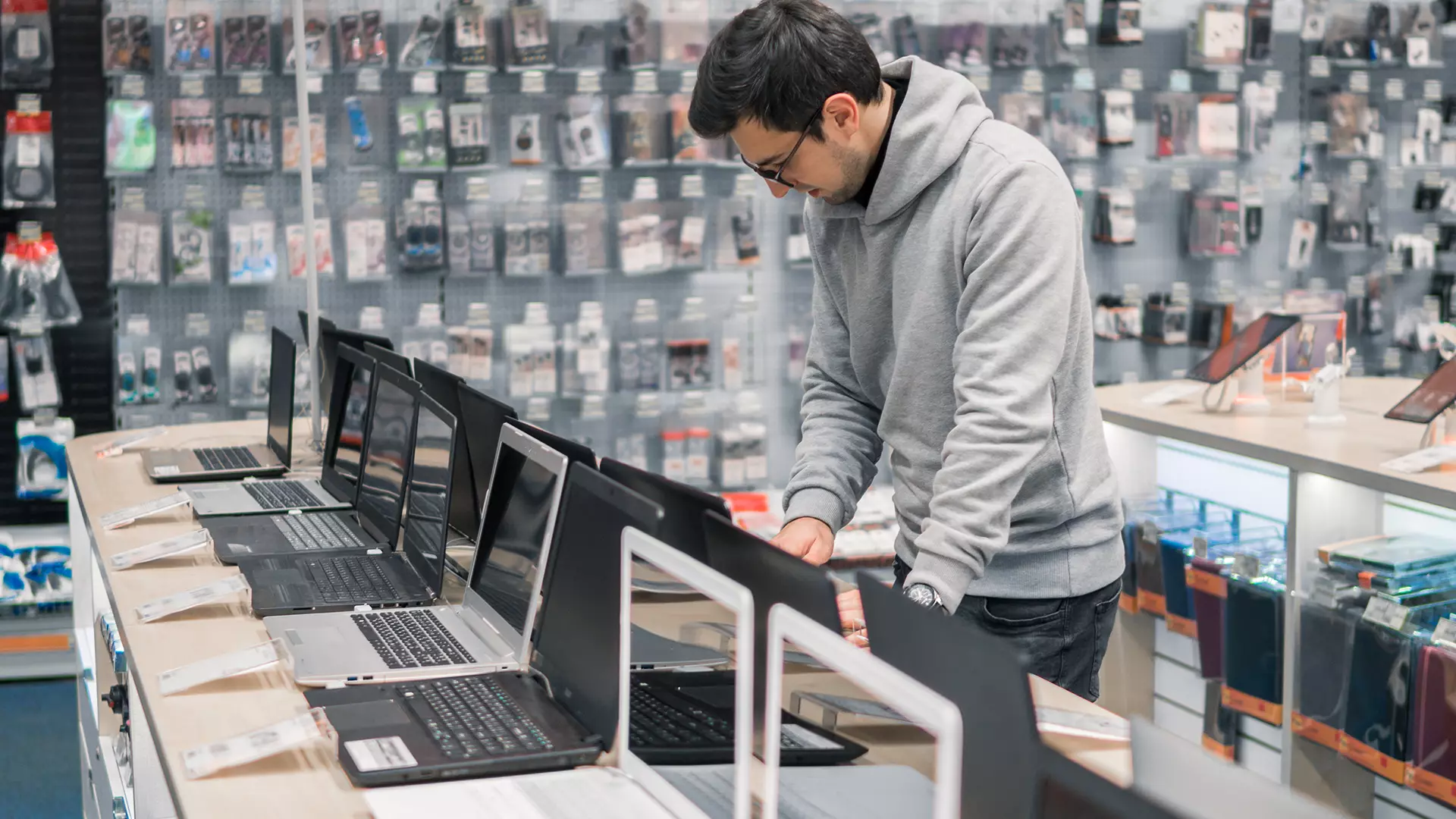 Um homem olhando para laptops em uma loja.