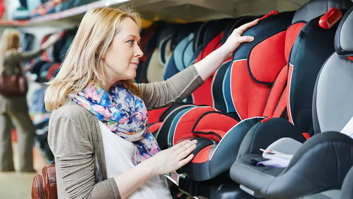 O femeie care se uită la scaunele de mașină dintr-un magazin.
