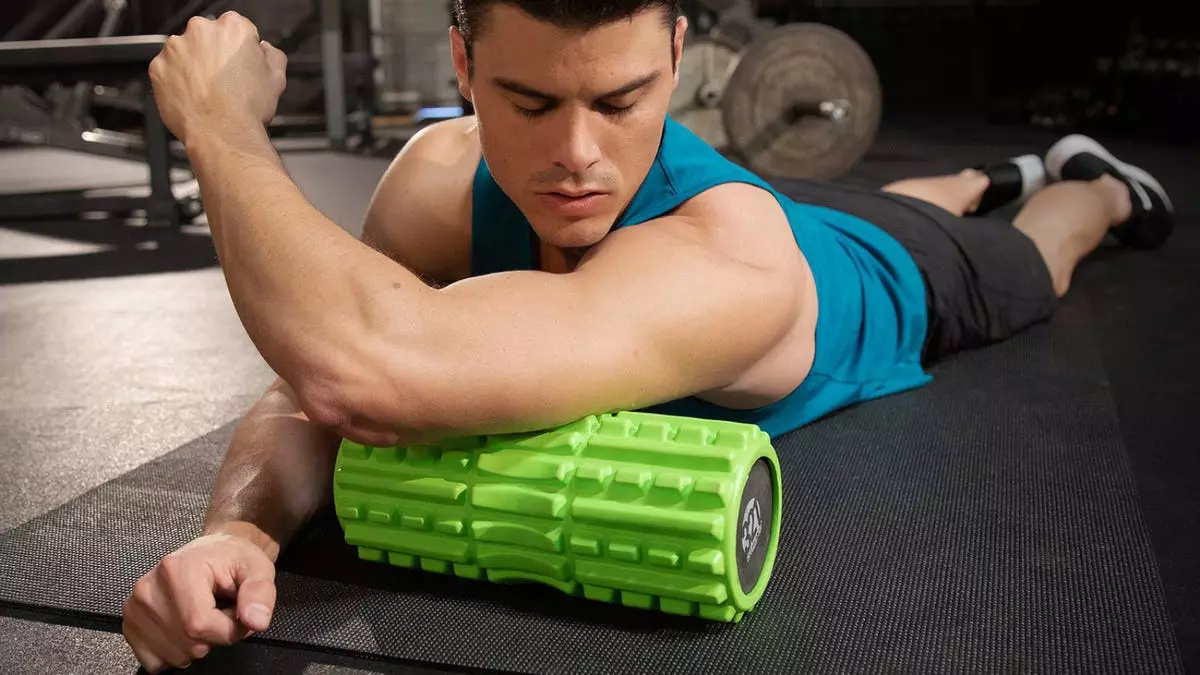 Un hombre acostado en una colchoneta de ejercicios usando un rodillo de espuma fuerte 321 con el brazo.