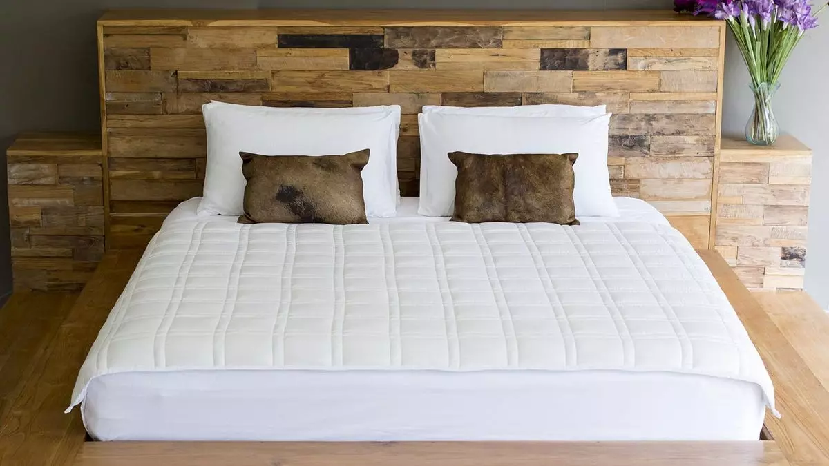 Manta blanca ponderada sobre una cama de plataforma de madera.