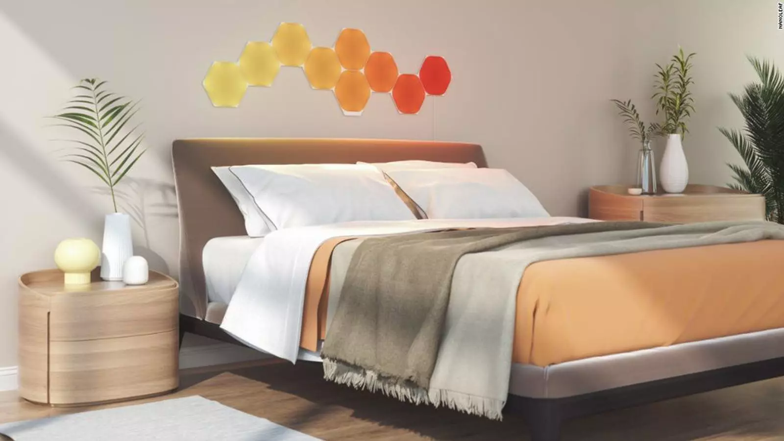 En seng i et moderne soverom, med 9 sekskantede LED-paneler opplyst i varierende nyanser av gult og oransje.