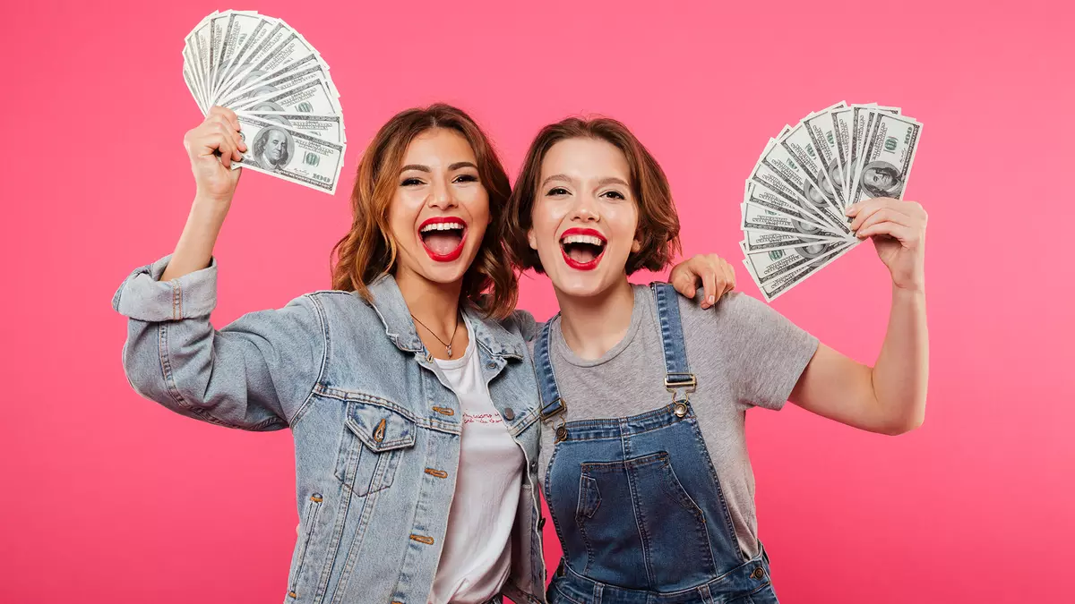 Två unga kvinnor som håller fläktar ut pengar.
