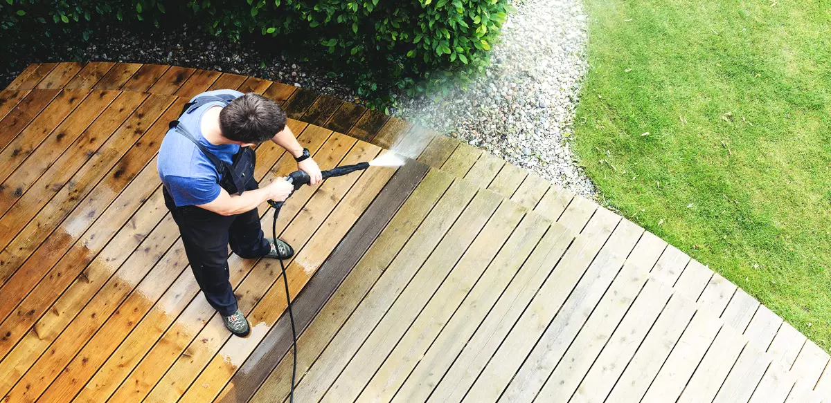 Un homme lave sa terrasse sous pression.