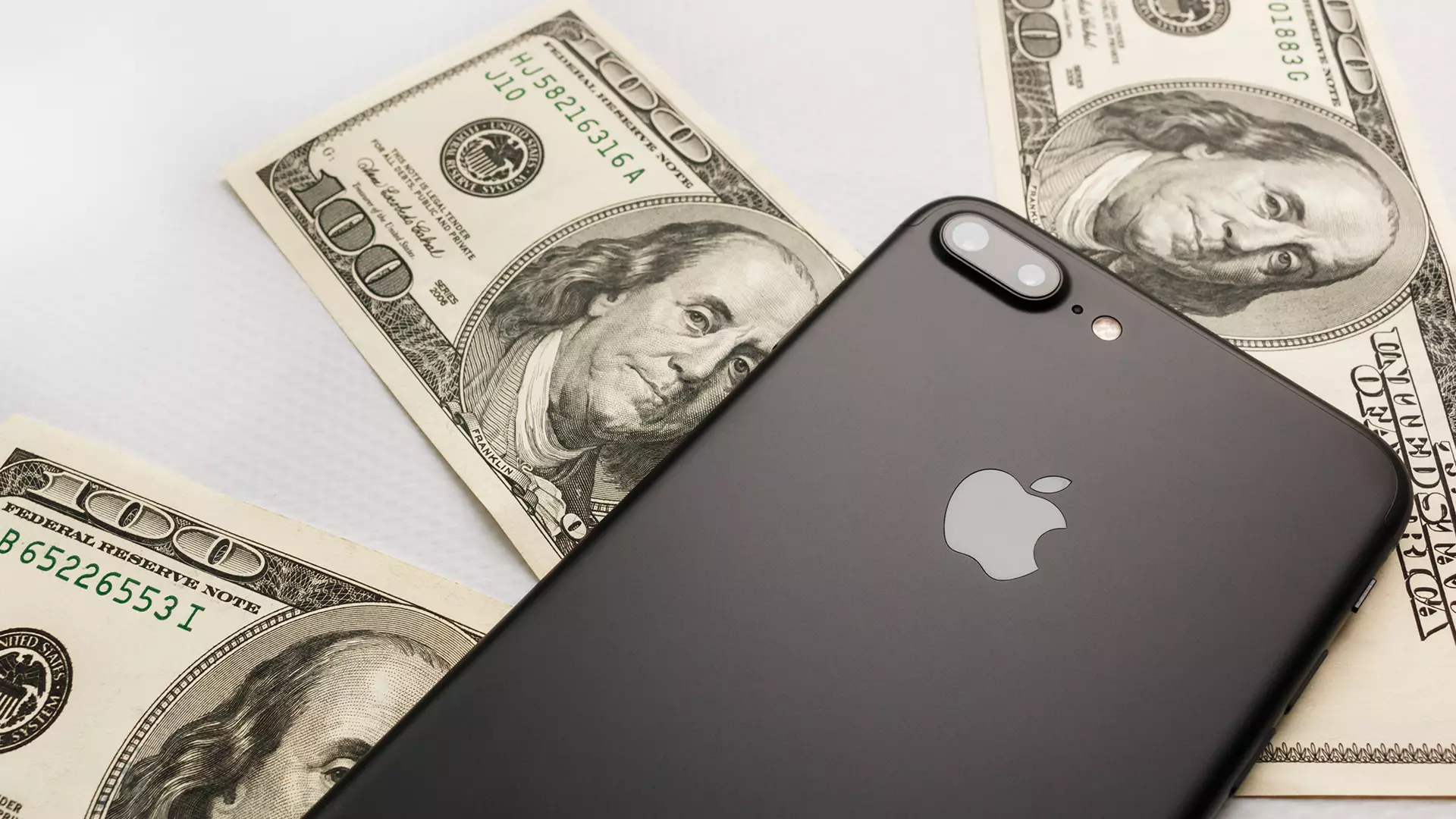 iPhone X วางอยู่บนธนบัตรสามใบมูลค่า 100 ดอลลาร์