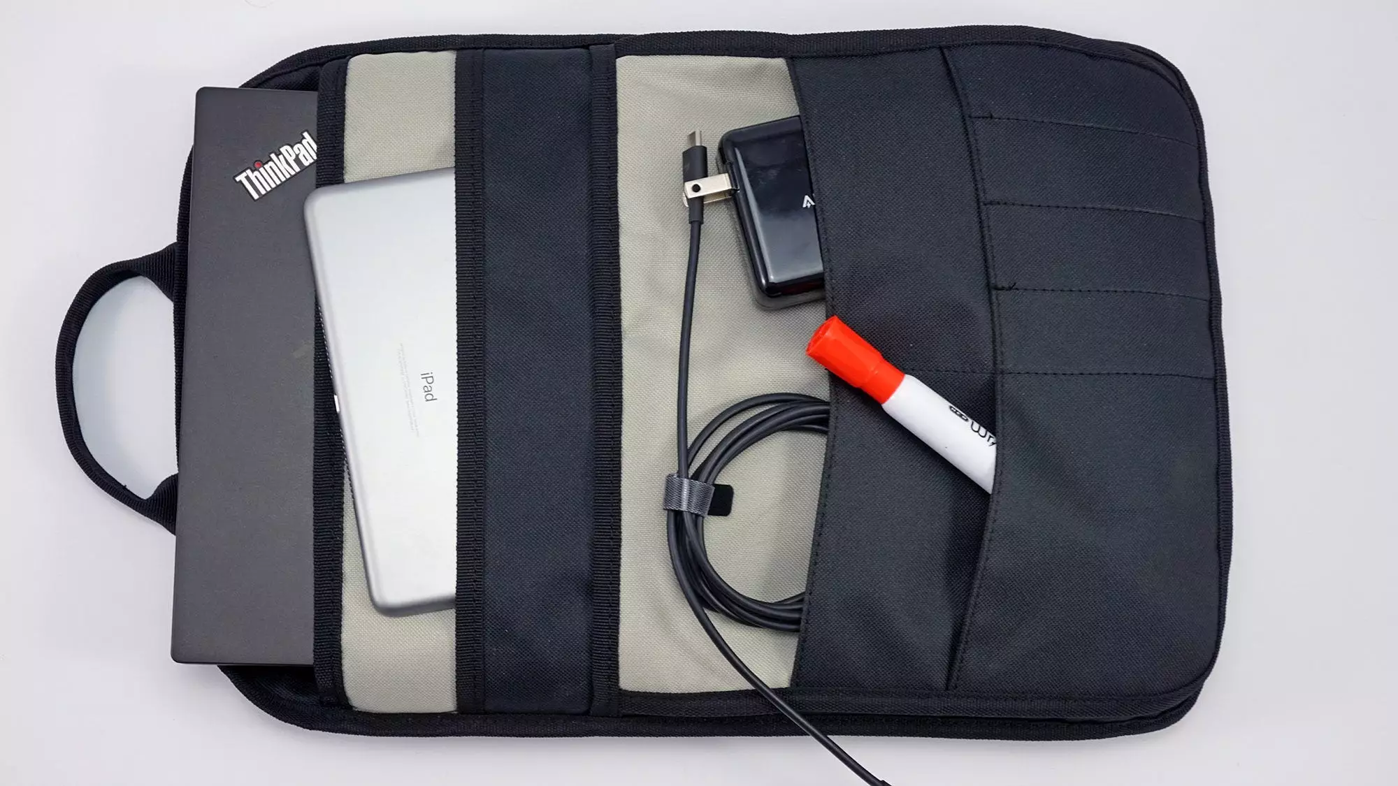 Pokrowiec organizacyjny z plecaka Booē Hybrid 20 z 2 tabletami, adapterem do gniazdka, przewodem i schowanym w nim markerem.