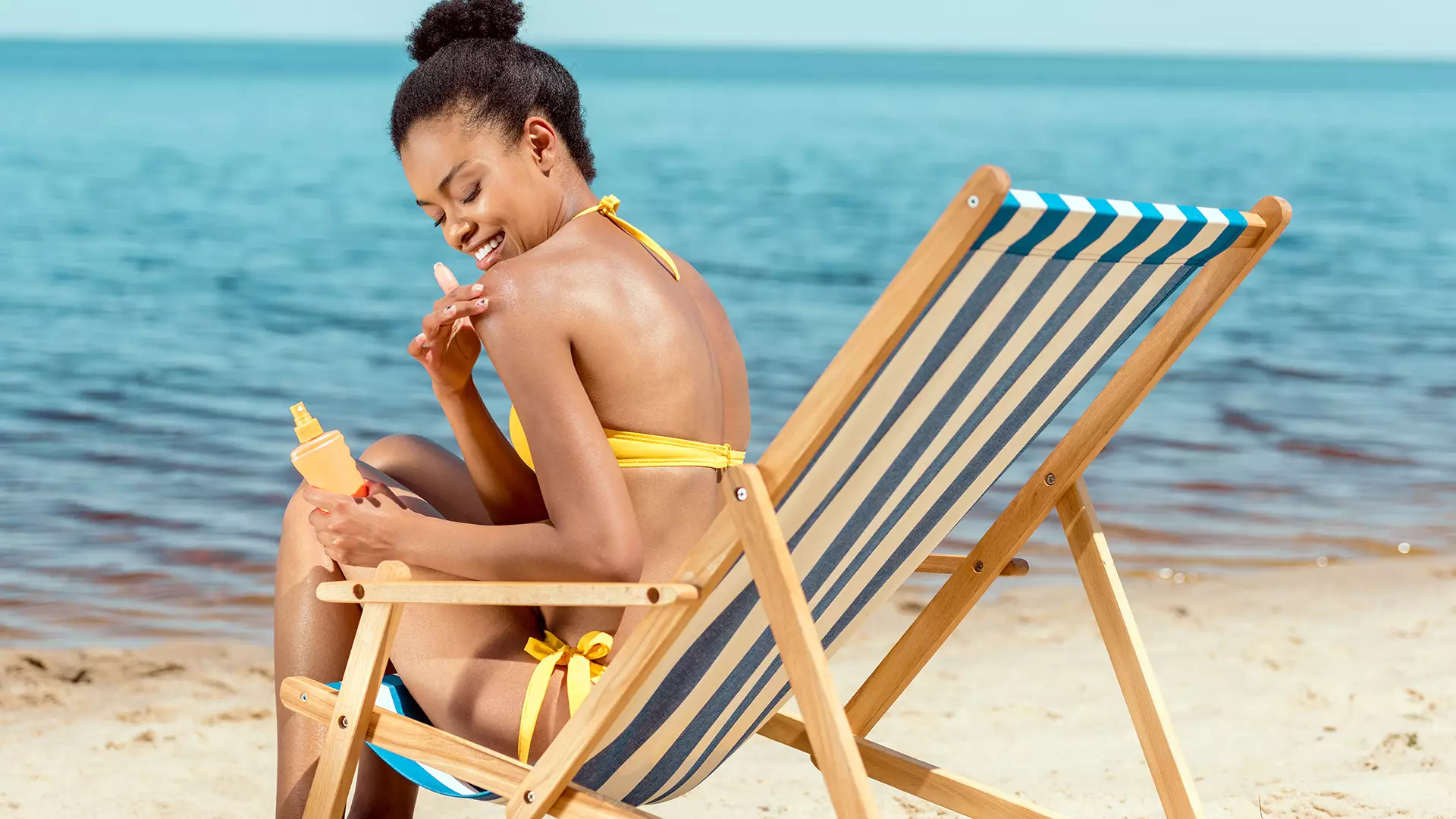 Nainen rannalla soveltamalla geeliä aurinkovoidetta.