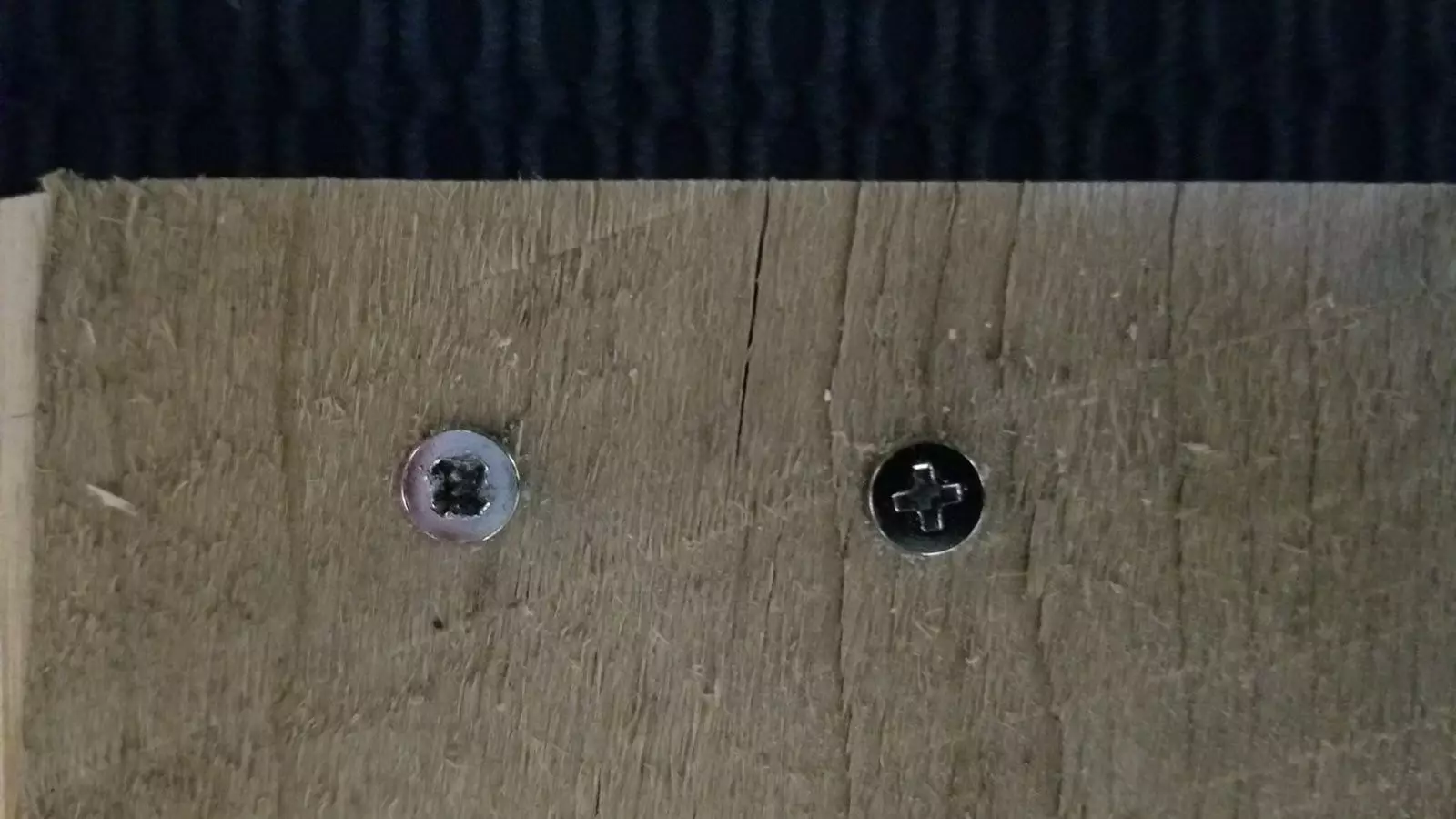 一块木板，里面有两颗螺丝，左边的螺丝被剥掉，右边的螺丝完好无损。