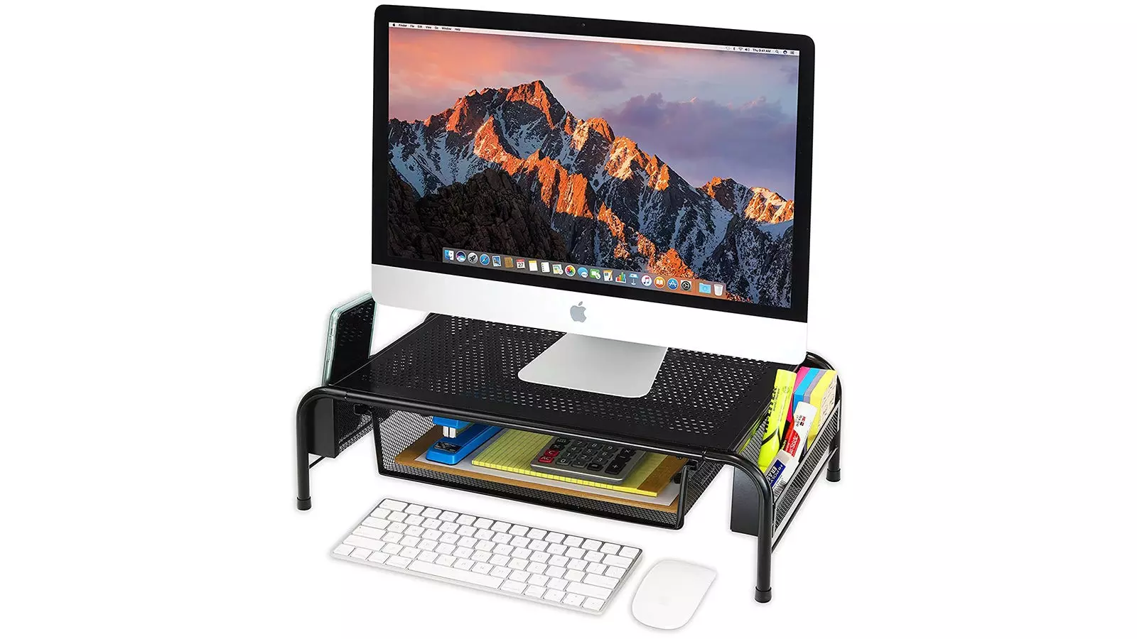 SimpleHouseware Metal Desk Monitor Riser med en Apple-skjerm på toppen, en stiftemaskin, kalkulator og notatblokker i hyllerommet, en telefon i venstre rom, og highlighters og Post-its i det høyre rommet.