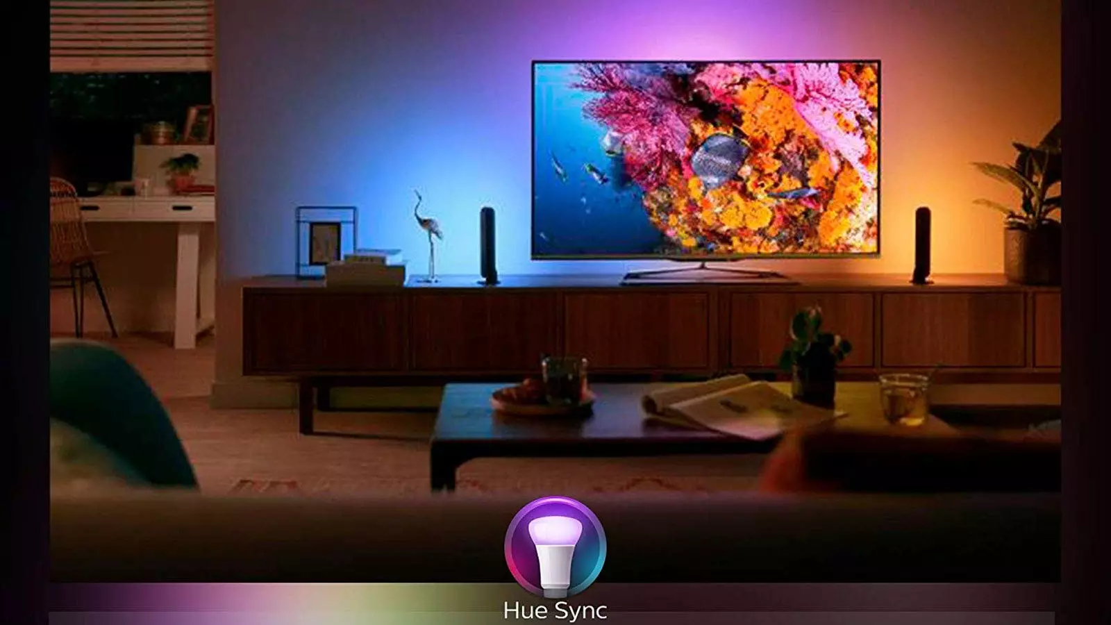 Ett vardagsrum upplyst med flera smarta lampor i blått, lila och orange.