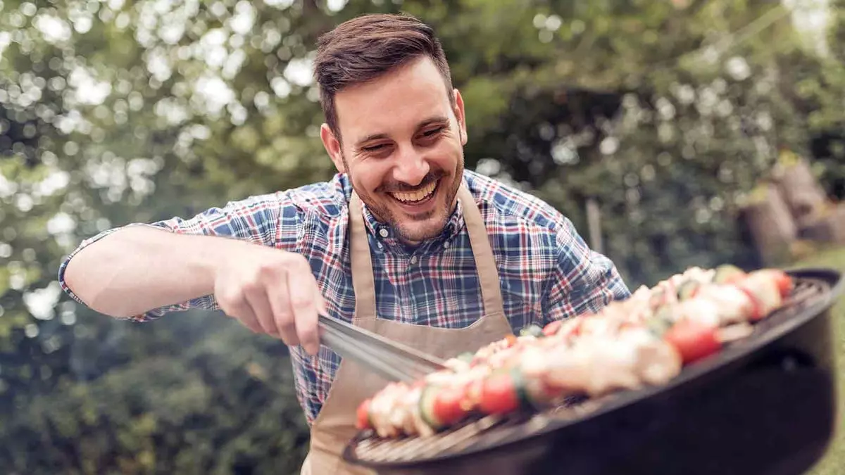 뒷마당 바비큐에서 고기를 굽고 있는 행복한 남자