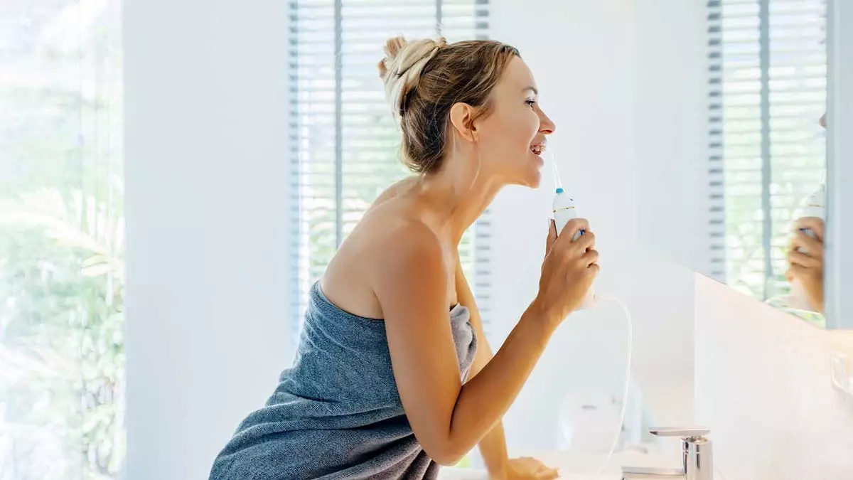 Dona utilitzant fil dental amb un fil d'aigua