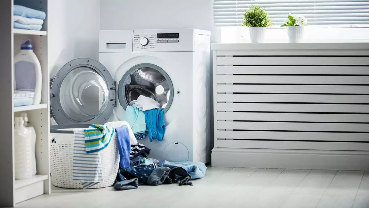 En bunke vasketøj foran en vaskemaskine