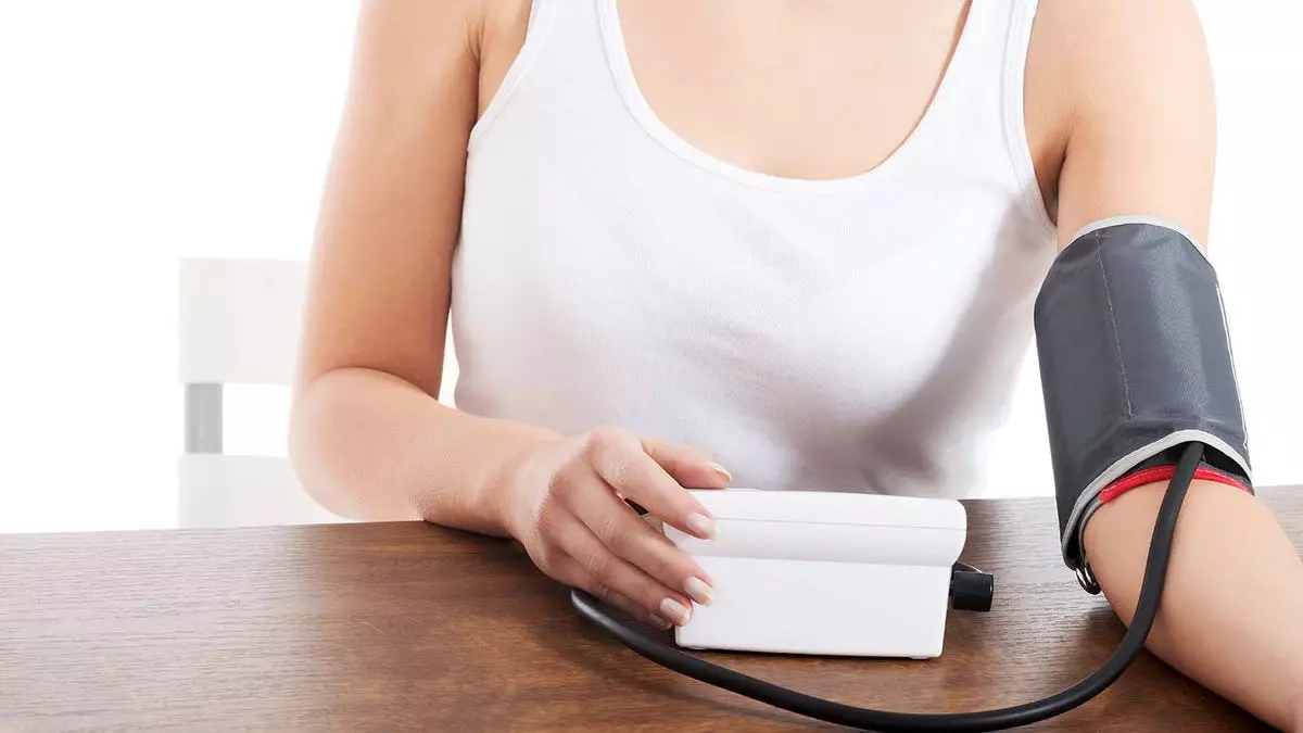 Nainen mittaa verenpainettaan kotona