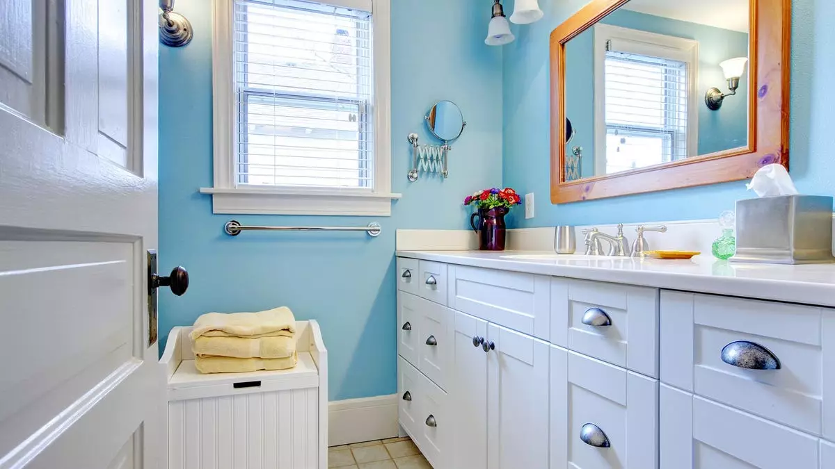 Blou en wit badkamer met baie pakplek met oop deur