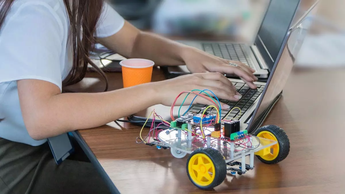 Mädchen programmiert einen Roboter mit einem Laptop