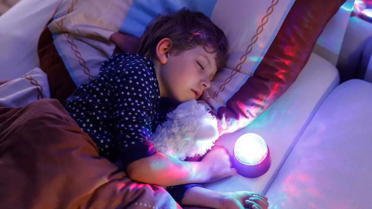 Niño durmiendo en la cama con un proyector de luz nocturna cerca