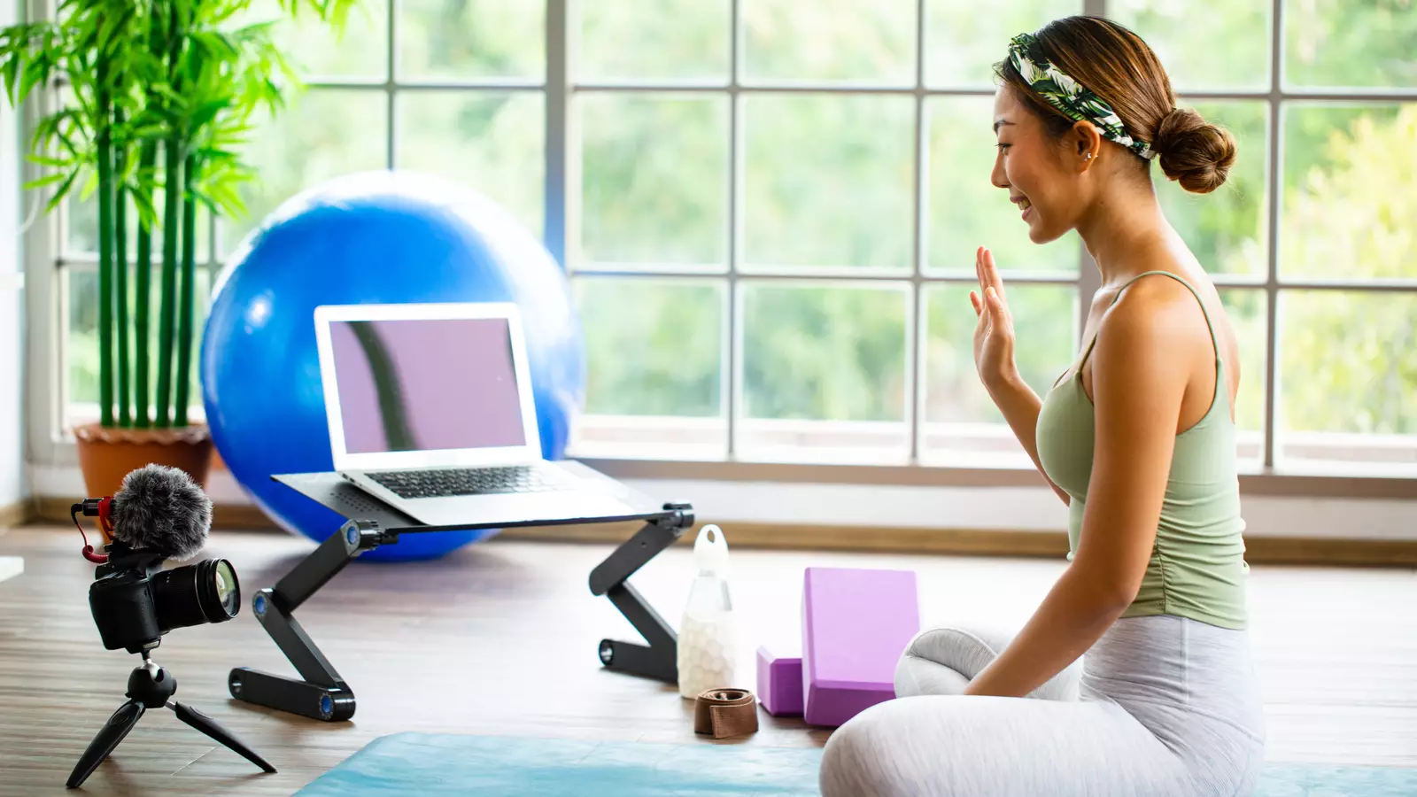 Orang yang menggunakan kamera DSLR untuk menstrim secara langsung pelajaran kelas yoga dalam talian