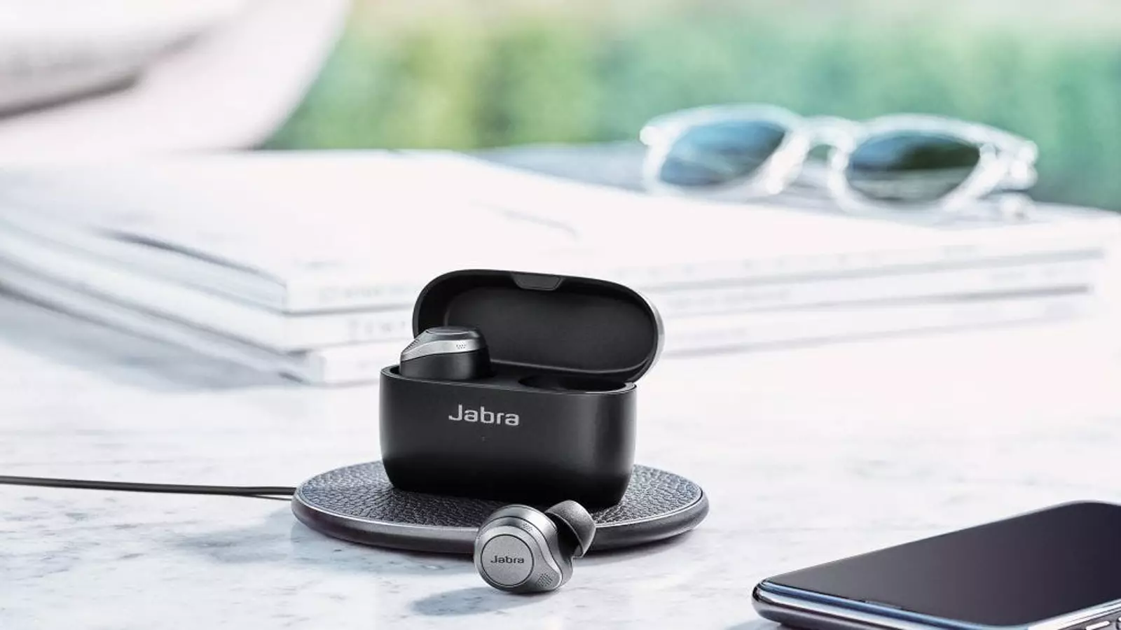 In set Jabra Elite 85T earbuds yn in koffer op in draadloze oplader.
