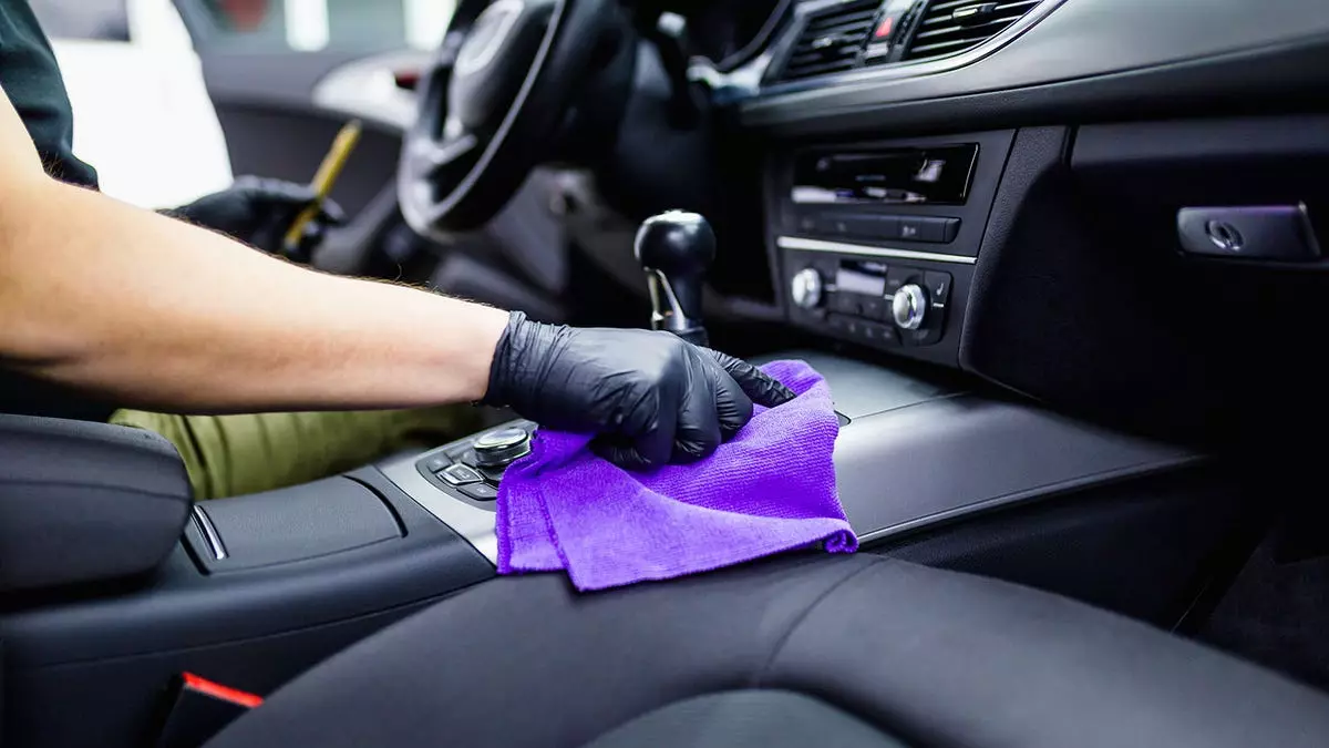 คนสวมถุงมือไนไตรล์ทำความสะอาดภายในรถด้วยผ้าไมโครไฟเบอร์